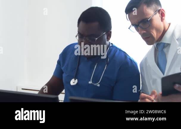 Doctor and surgeon working in hospital office using computer technology ...