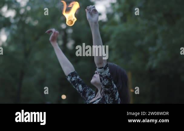 Cute young grace girl performing a show with flame standing in front of ...