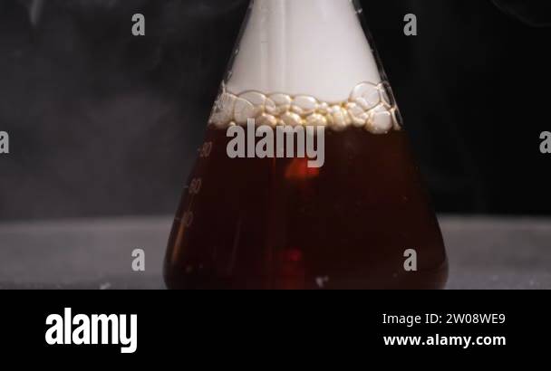Flask with dark reagent and steam in chemical lab. Close-up view of ...
