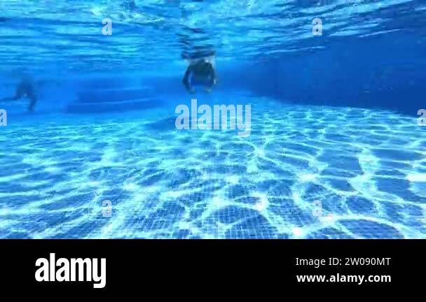 Man underwater. Blue transparent water inside the swimming pool and a ...