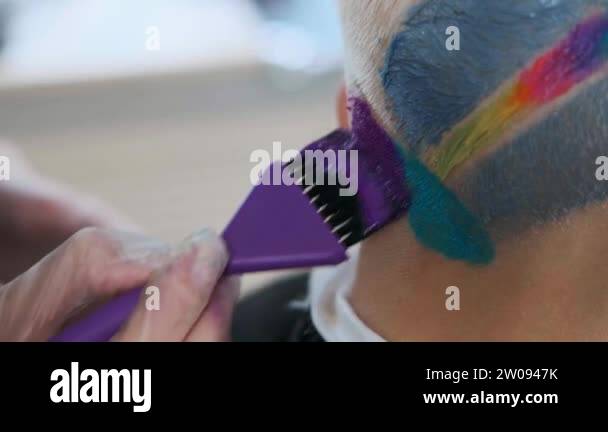 Hairdresser colorist puts paint on the hair with a brush. A short ...