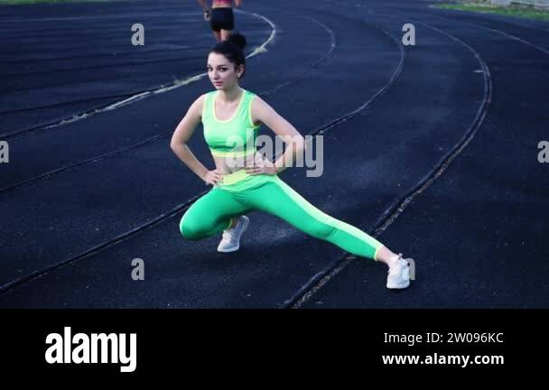 beautiful young girl in green sports leggings does warm-up for legs in ...