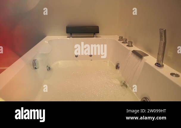 Water flows in jacuzzi. Spa bathroom with hydromassage and foam ...