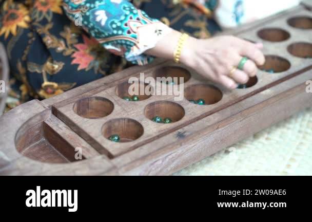 Woman hand playing congkak, traditional Malay two player game in which ...