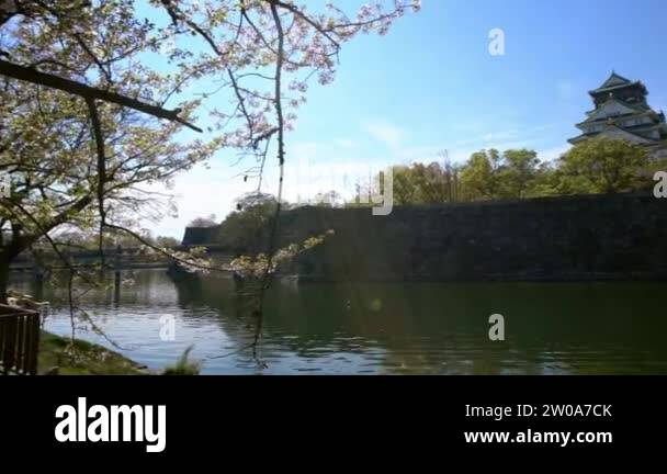4K, Main tower of Osaka Japanese Castle behind rock wall and the moat ...