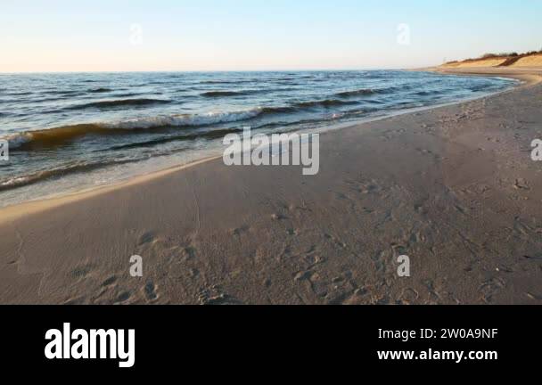 Baltic sea at sunset, sandy beach, soft waves and mild water overflows ...