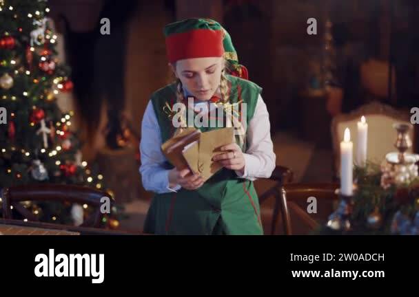 Funny elf holding stack of envelopes for Santa. Dispersed young elf ...