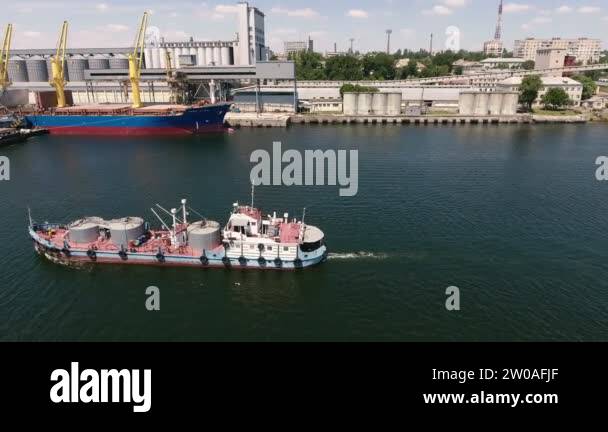 Aerial shot of a small barge moving along a river embankment on a sunny ...