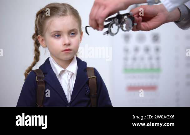 Optometrist putting optical trial frame on schoolgirl to determine ...