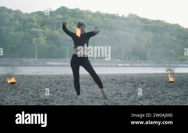 Confident slim woman in mask dancing, performing a show with fireball ...