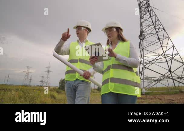 Engineer and supervisor with tablet PC and the drawings are about lines and transmission towers ...