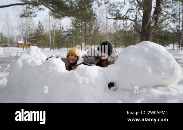 Mom, son and dad are hiding behind snow wall and throwing snowballs ...