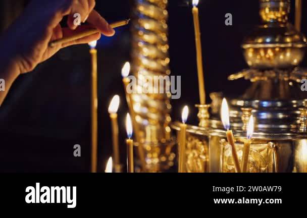Woman's hand lighting a candle and putting it among other candles in a ...