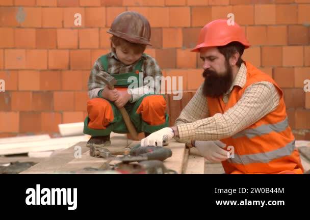 Son and Father puts a brick to build a wall. Work with tools. Little ...