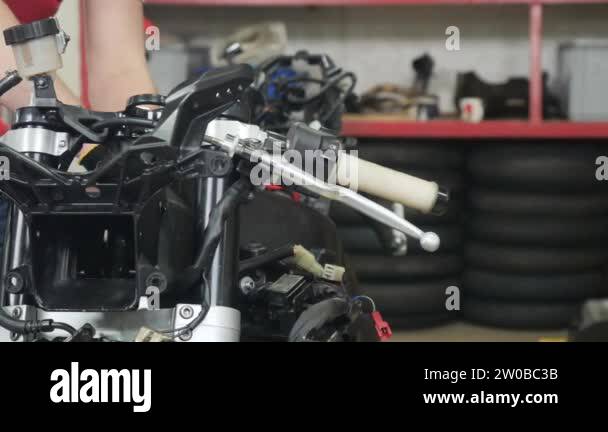 Engineer repair motor of motorcycle. The man twists the nut with ...