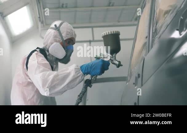Male worker is colouring the automobile with the airbrush. Industrial ...