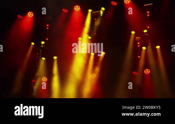 Red and yellow spotlights flash in the fog at a rock concert in the ...