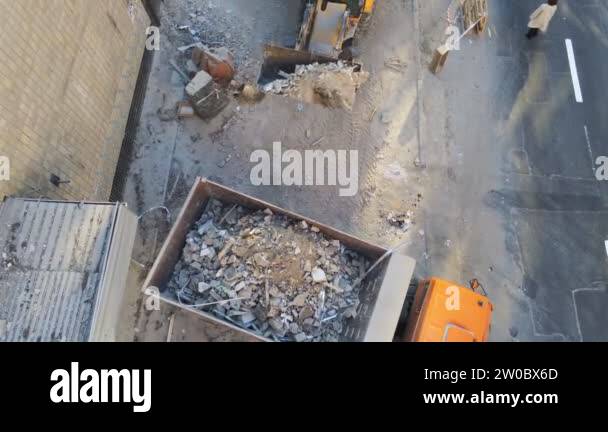 Bulldozer loader uploading waste and debris into dump truck at ...
