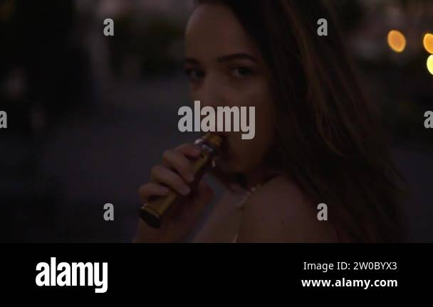 Girl smokes a vape on the background of the moon and the city of the ...