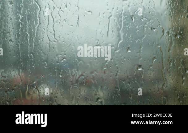 Closeup raindrops water droplets trickling down on wet clear window glass during heavy rain ...