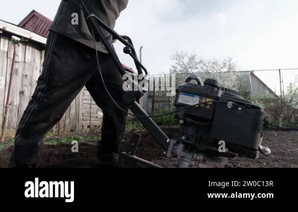 old man plowman plows the earth with a big effort motoblock. Very hard work. his wife is working ...