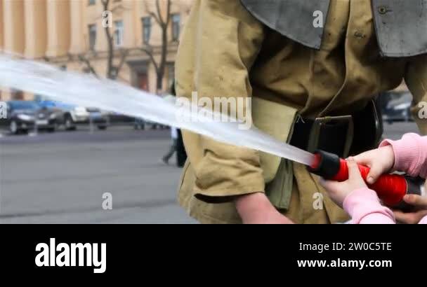 fireman in a special form teaches children to hold the fire hose for ...