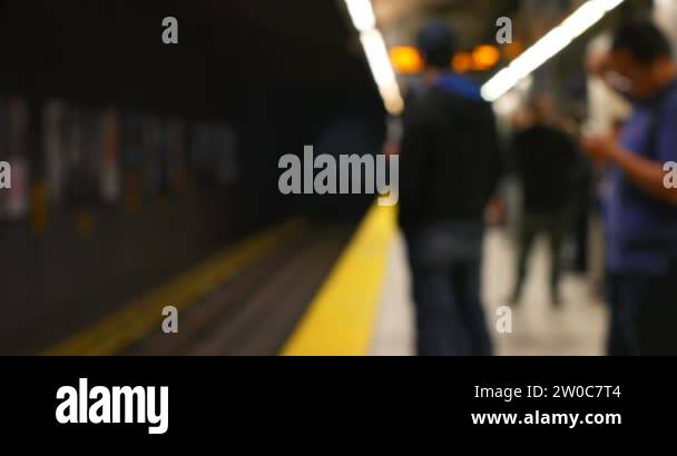 Side view of commuters waiting for train on subway platform. Blurred ...