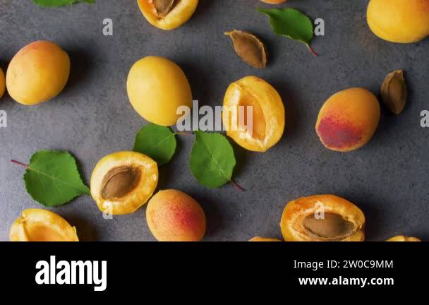 Nice yummy fresh sliced apricots with green tree leaves on dark texture ...