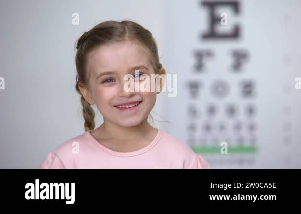 Adorable child girl laughing after vision test on eye chart, healthy ...