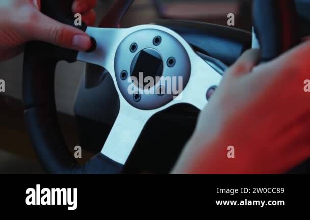 Close-up of the hands of a young gamer behind the steering wheel of a ...