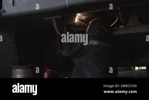 Welder at work. Welder repairs large trucks. Slow motion shooting of ...