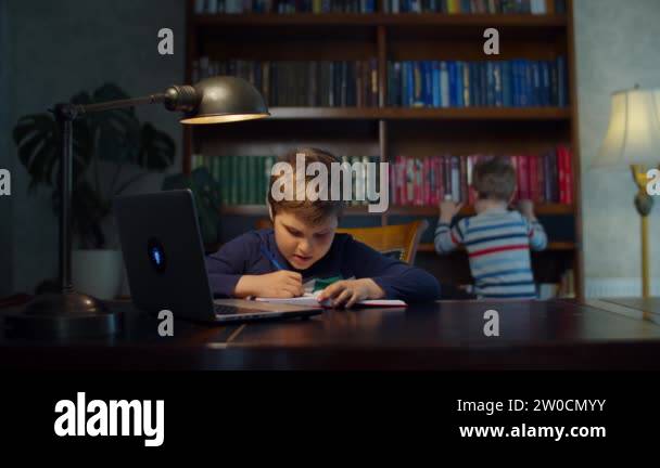 School boy making online school homework with laptop at home. Younger ...