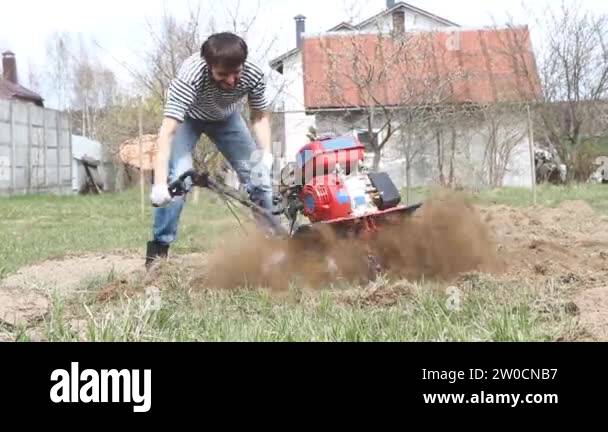 Close up, Man plowing the land in the garden with a cultivator ...