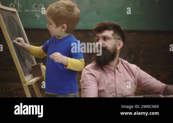 Pupil with teacher at school. Side view father and son learn arithmetic ...