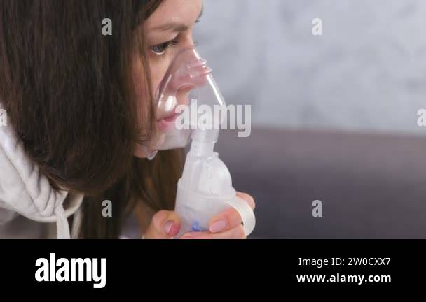 Use nebulizer and inhaler for the treatment. Young woman inhaling ...