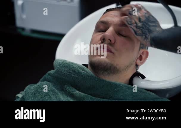 Attractive male is getting a modern haircut in barber shop. Top view of ...