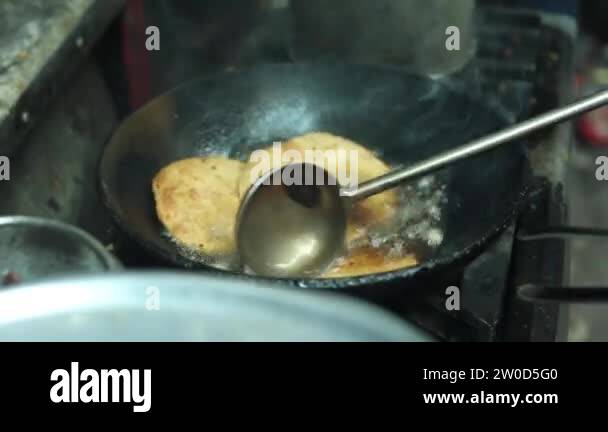Indian bread paranthas being deep fried in hot oil. Street food in ...