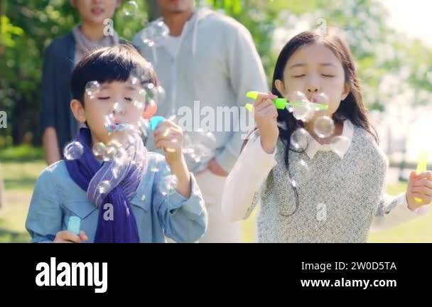 two little asian children boy and girl playing outdoors blowing soap ...
