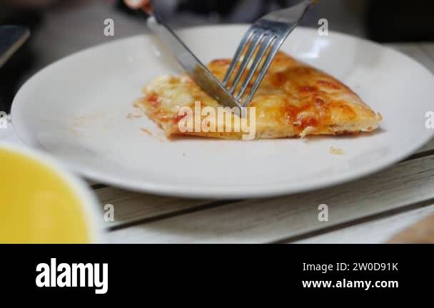 Woman cuts a piece of pizza with a knife and fork. Delicious food for ...