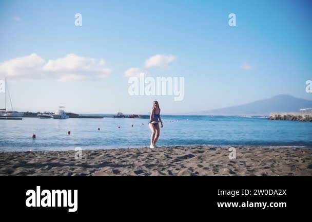 A young man playing frisbee on the beach with his female friend ...