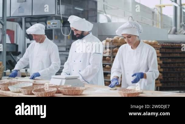 Attractive woman baker and her colleagues bakers working fast in a ...