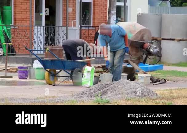 Builders knead concrete mortar with a concrete mixer for building a new ...