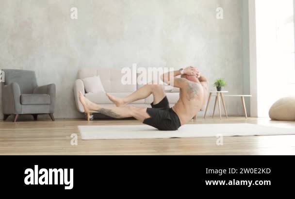 Sporty muscular man is doing abs exercises crunches at home on floor ...