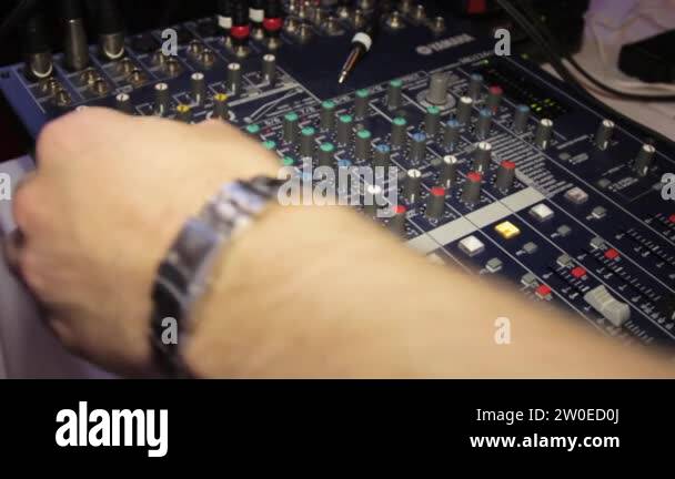 DJ behind console, on stage, mixing tracks in atmospheric dance party ...