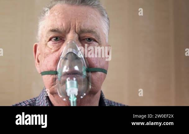 Portrait of an elderly man with COPD in an oxygen mask is breathing ...