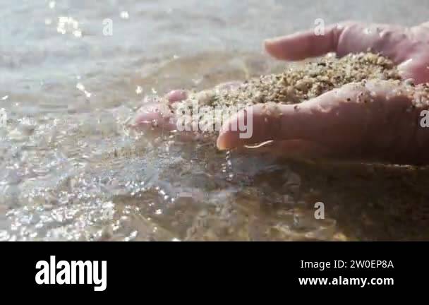 Two palms holding sand on the Alanya beach in summer in slow motion ...