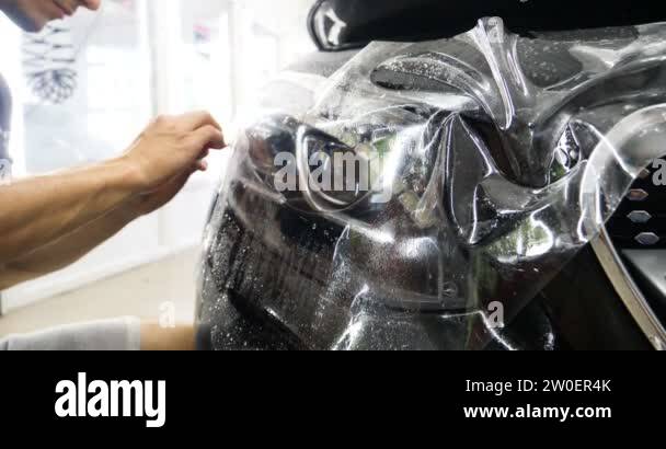Close up to PPF installation process on a front headlight and hood. PPF ...