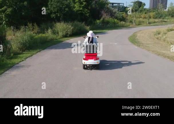 Disabled person driving a motorized mobility scooter for elderly and or ...