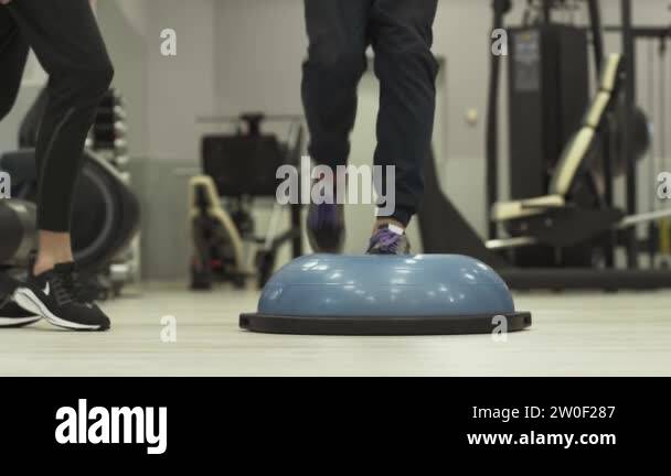 Close-up feet of the man doing exercises for legs in the gym while his ...