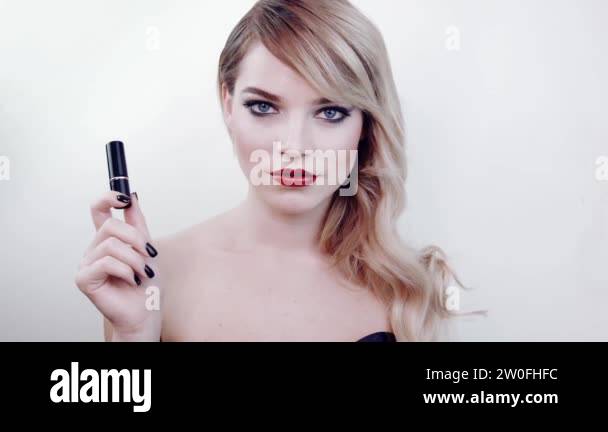Beautiful girl holds lipstick in front her,opens her lipstick,looks ...
